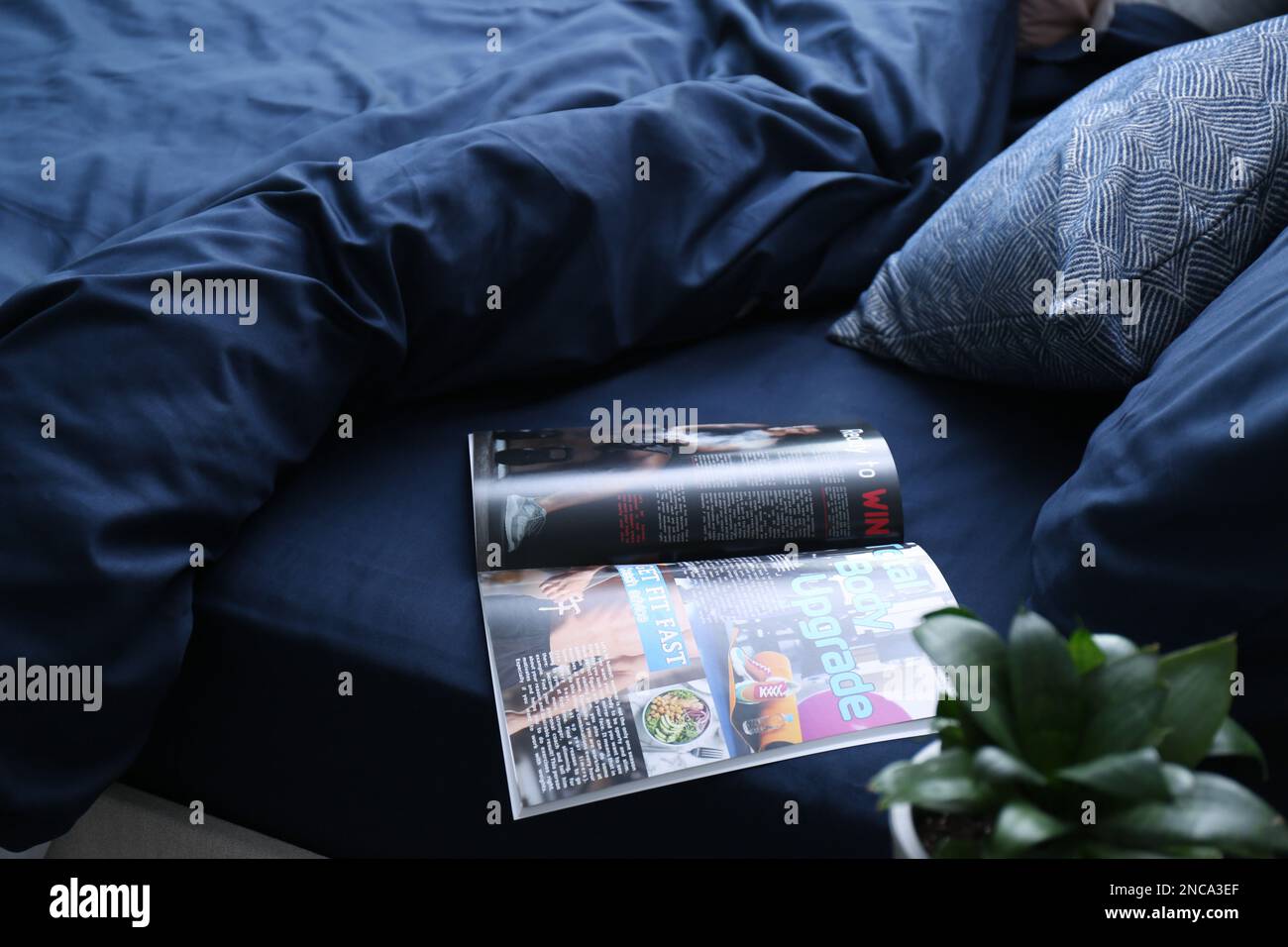 Open magazine on bed with stylish silky linens Stock Photo - Alamy