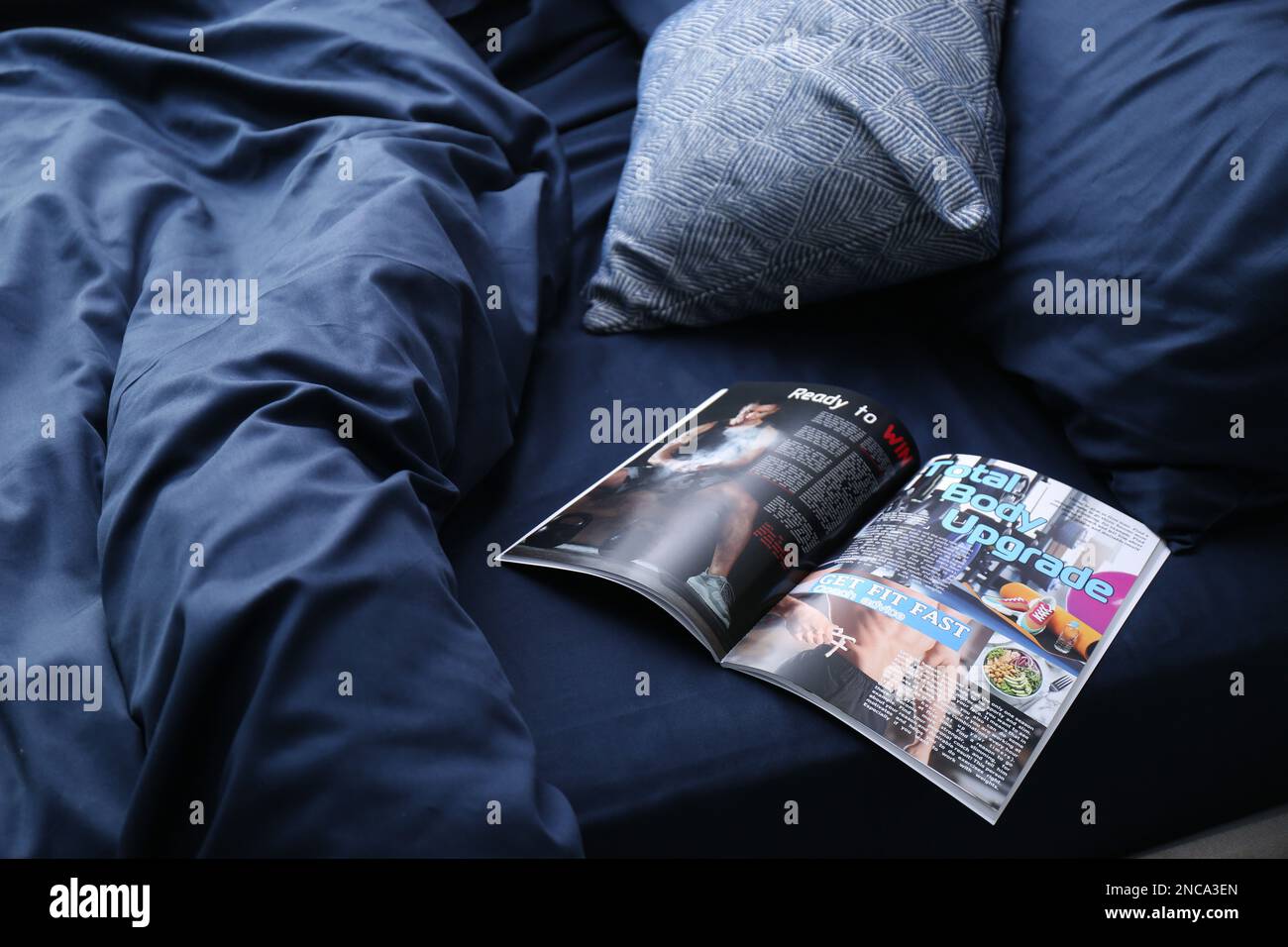 Open magazine on bed with stylish silky linens Stock Photo - Alamy