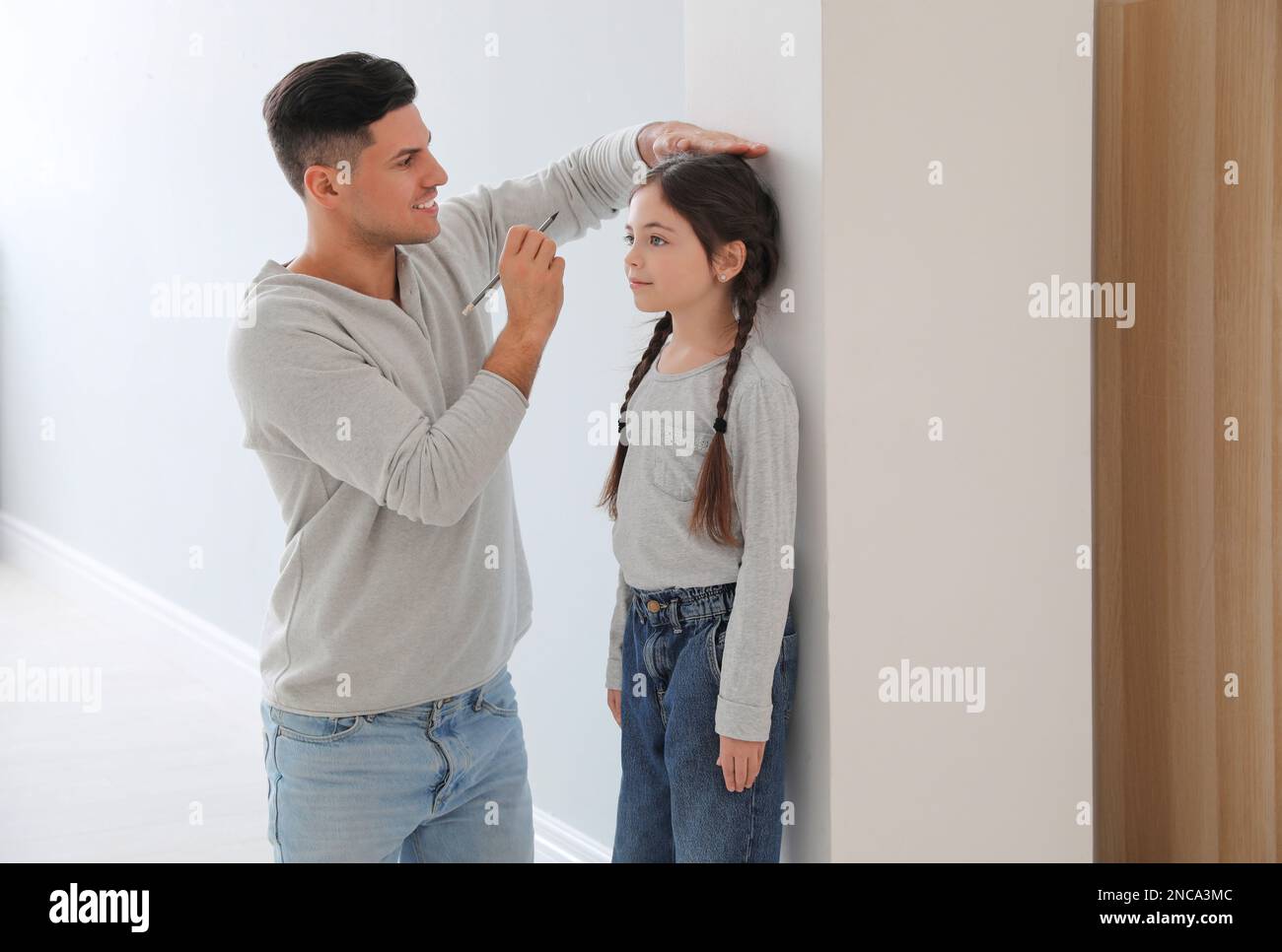 Father measuring height of his daughter near wall indoors Stock Photo ...