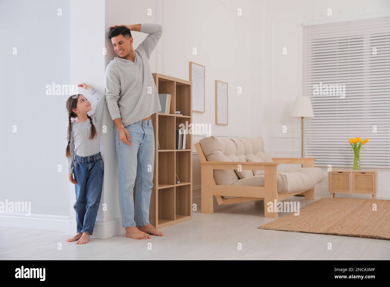 Little girl and father measuring their height near wall at home Stock ...