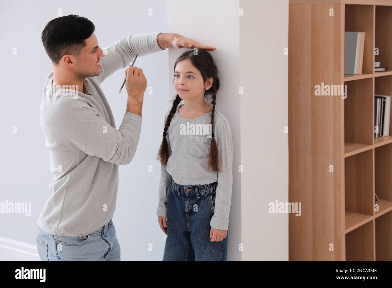 Father measuring height of his daughter near wall indoors Stock Photo ...