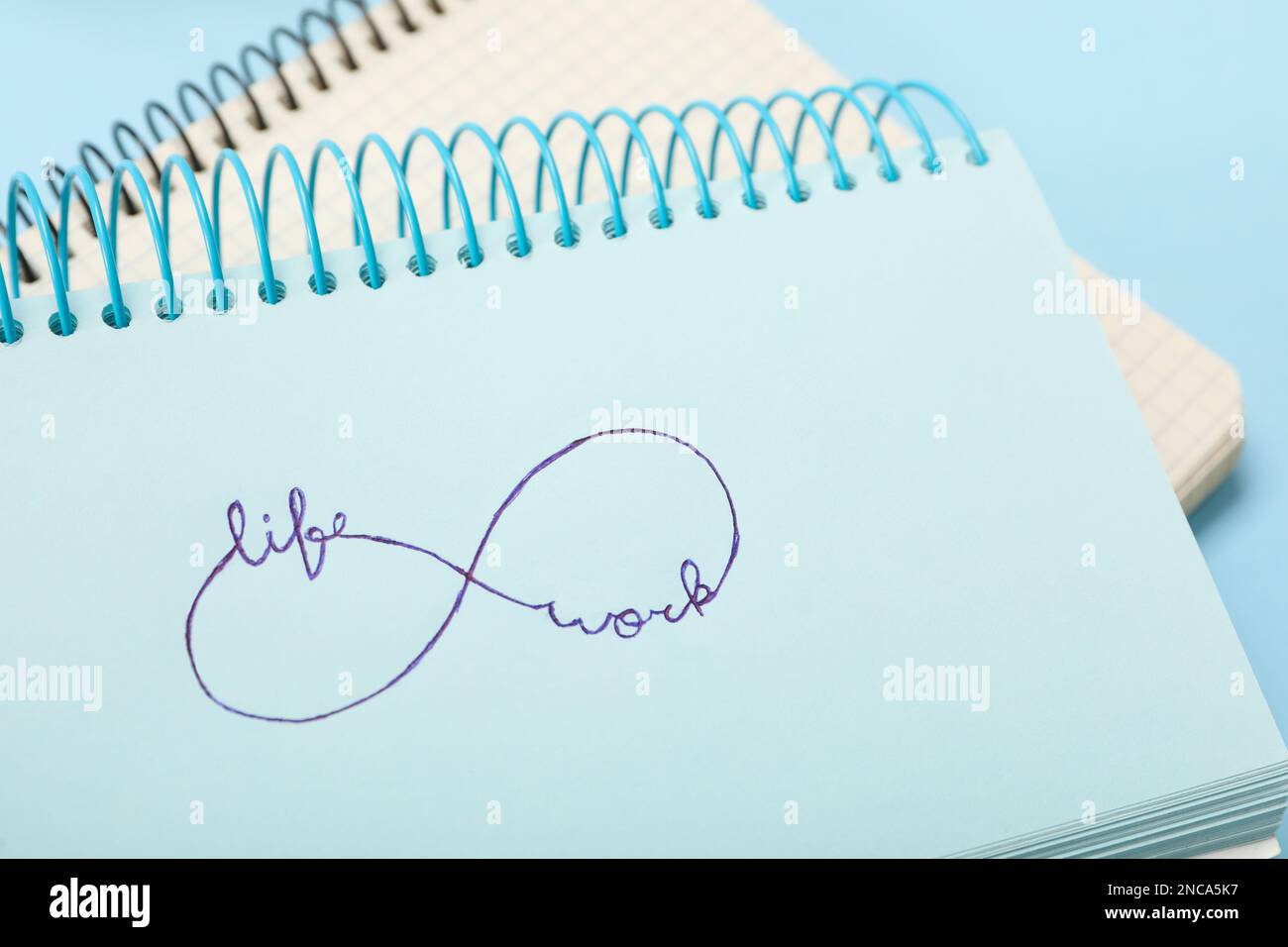 Drawn infinity sign with words Work and Life in notebook on light blue ...