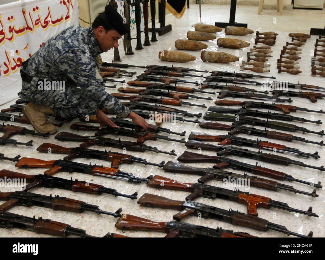 An Iraqi policeman arranges weapons seized by Iraqi security forces ...