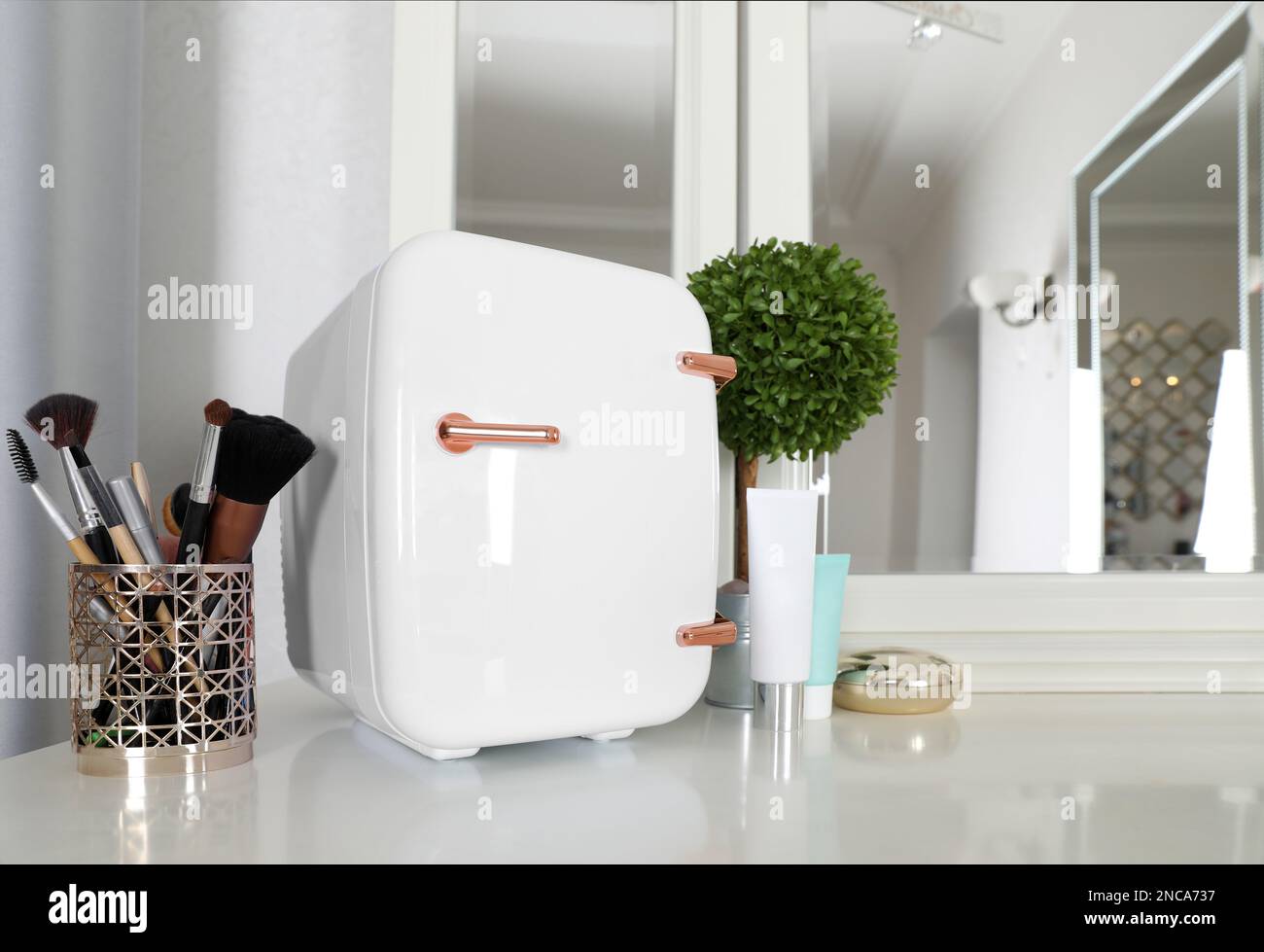 Mini fridge for cosmetic products on white vanity table Stock Photo - Alamy