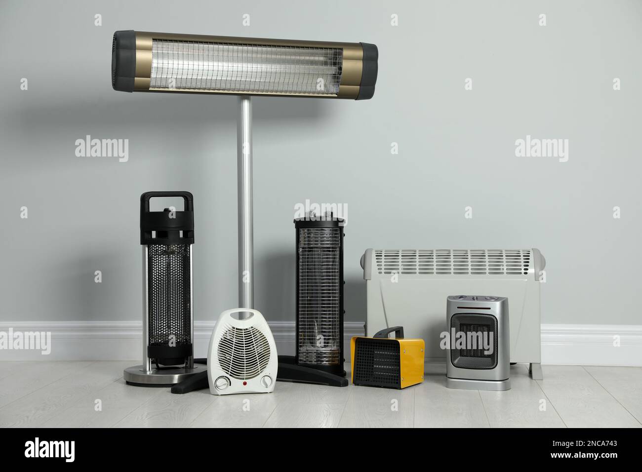 Different electric heaters near light grey wall indoors Stock Photo - Alamy