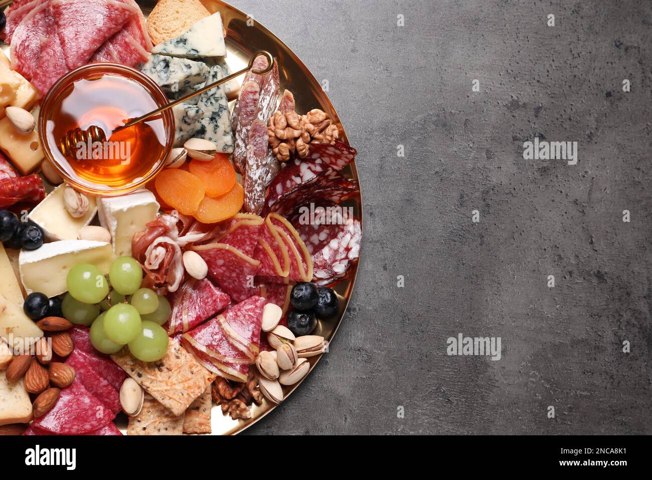 Plate of different appetizers with honey on grey table, top view. Space ...
