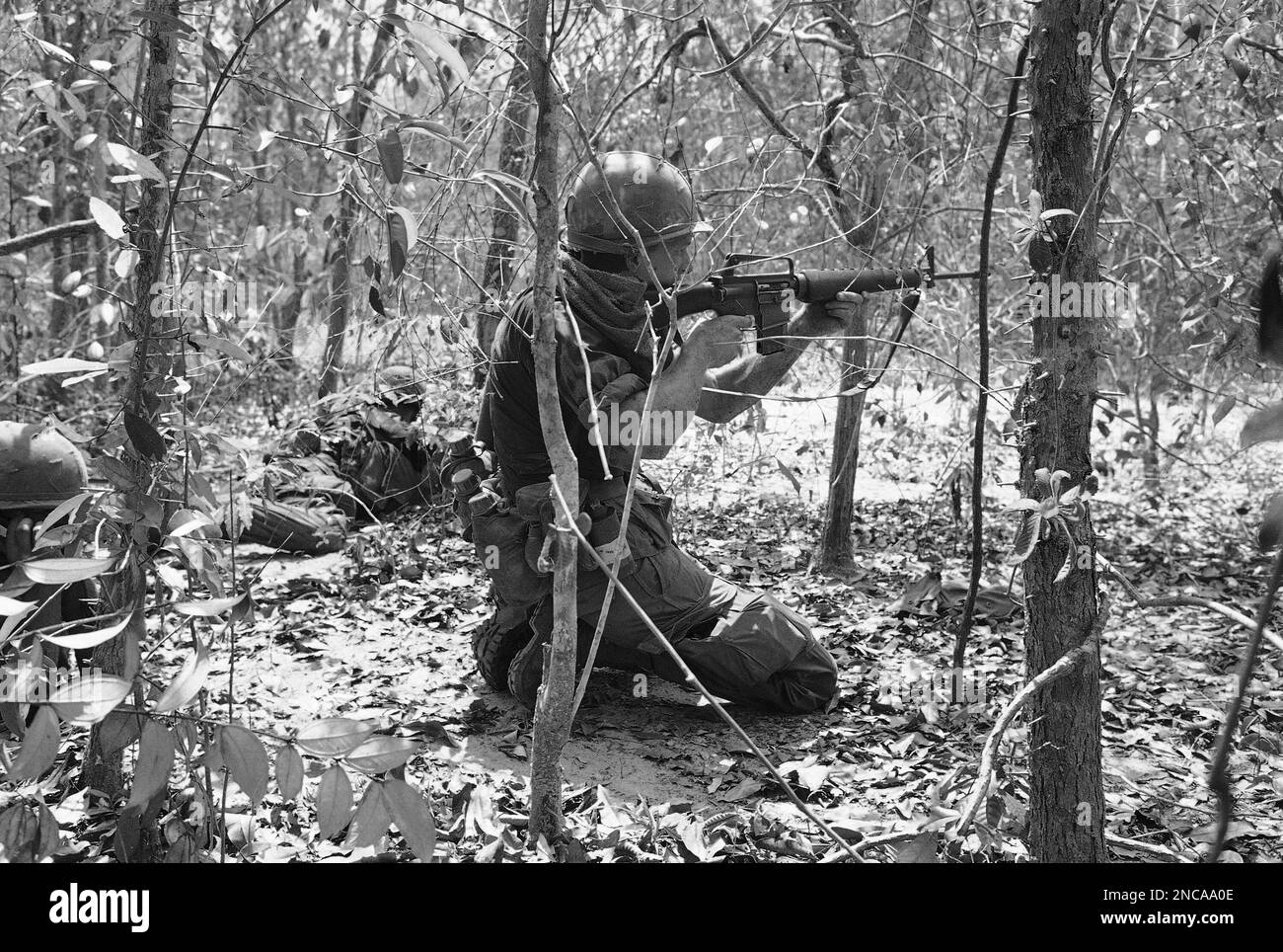 A U.S. rifleman aims his M16 towards a Vietcong bunker entrance from ...