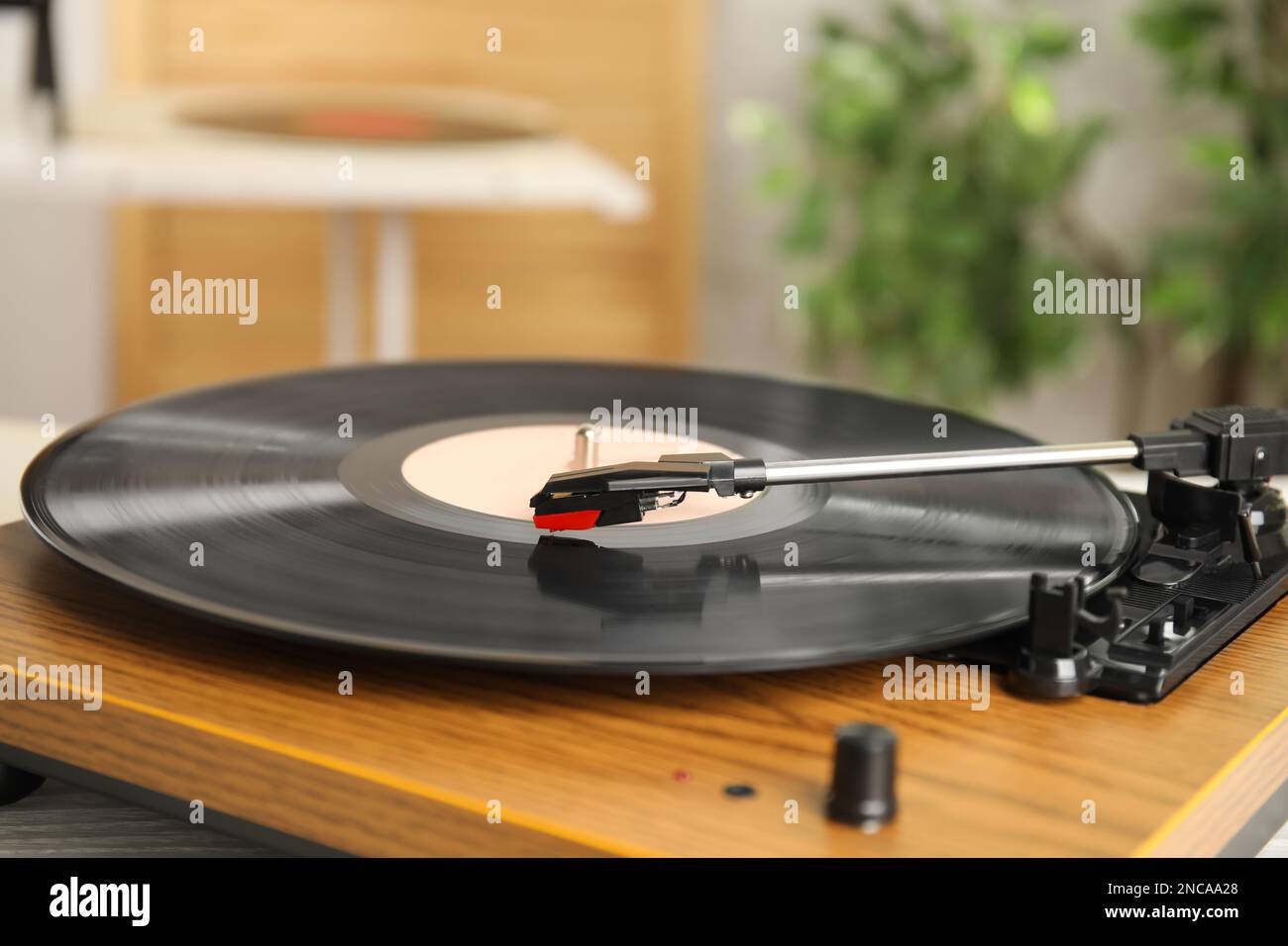 Turntable with vinyl record on blurred background, closeup. Space for ...