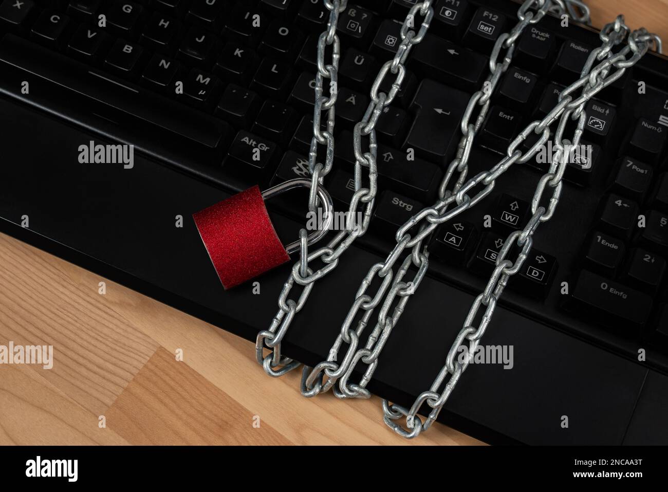 The computer keyboard is wrapped with a metal chain with a lock. Close ...