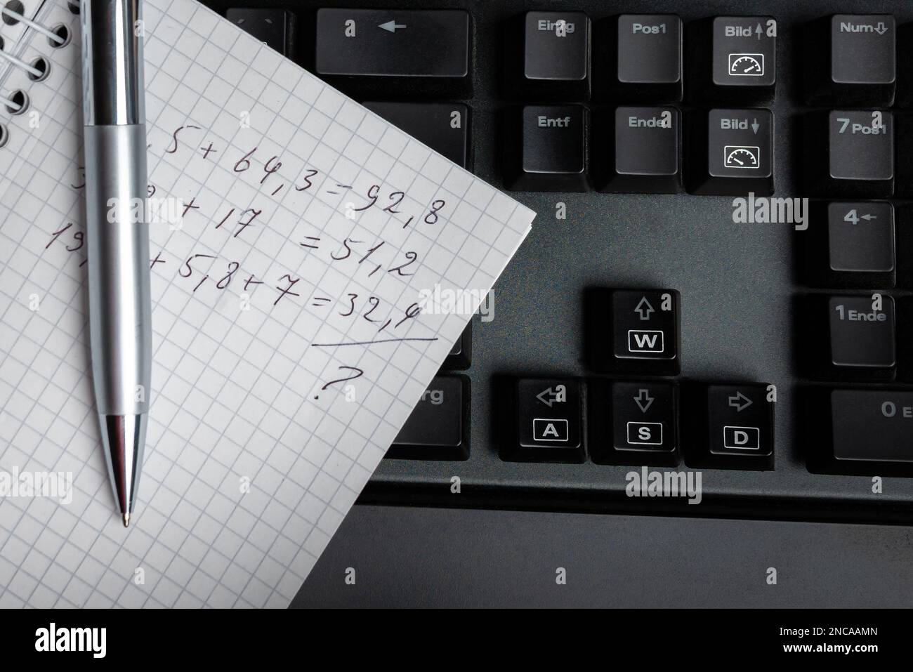 Ballpoint pen and sheet of notes with arithmetic calculations on pc ...