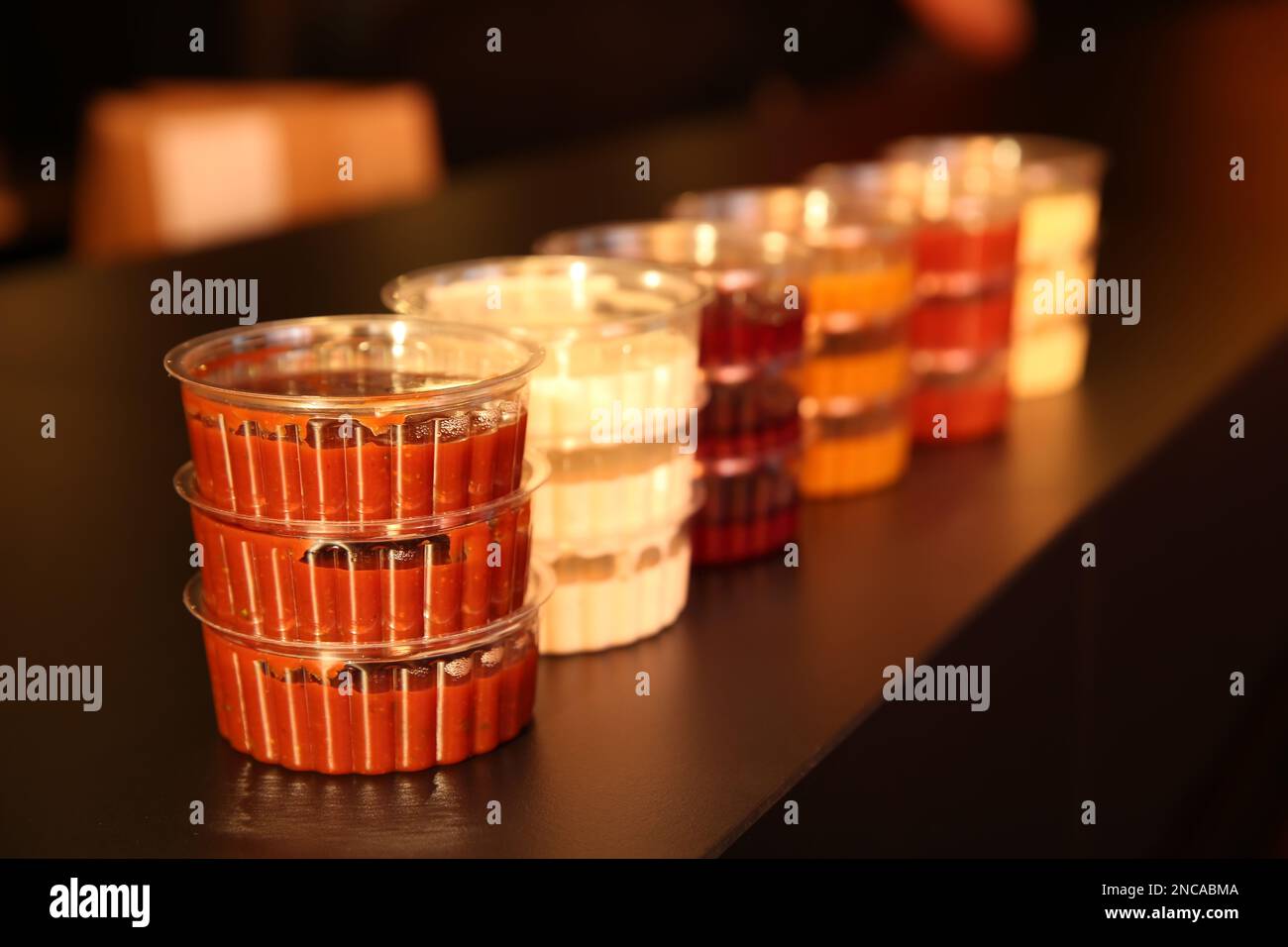 Set of delicious sauces in plastic containers on black counter indoors ...