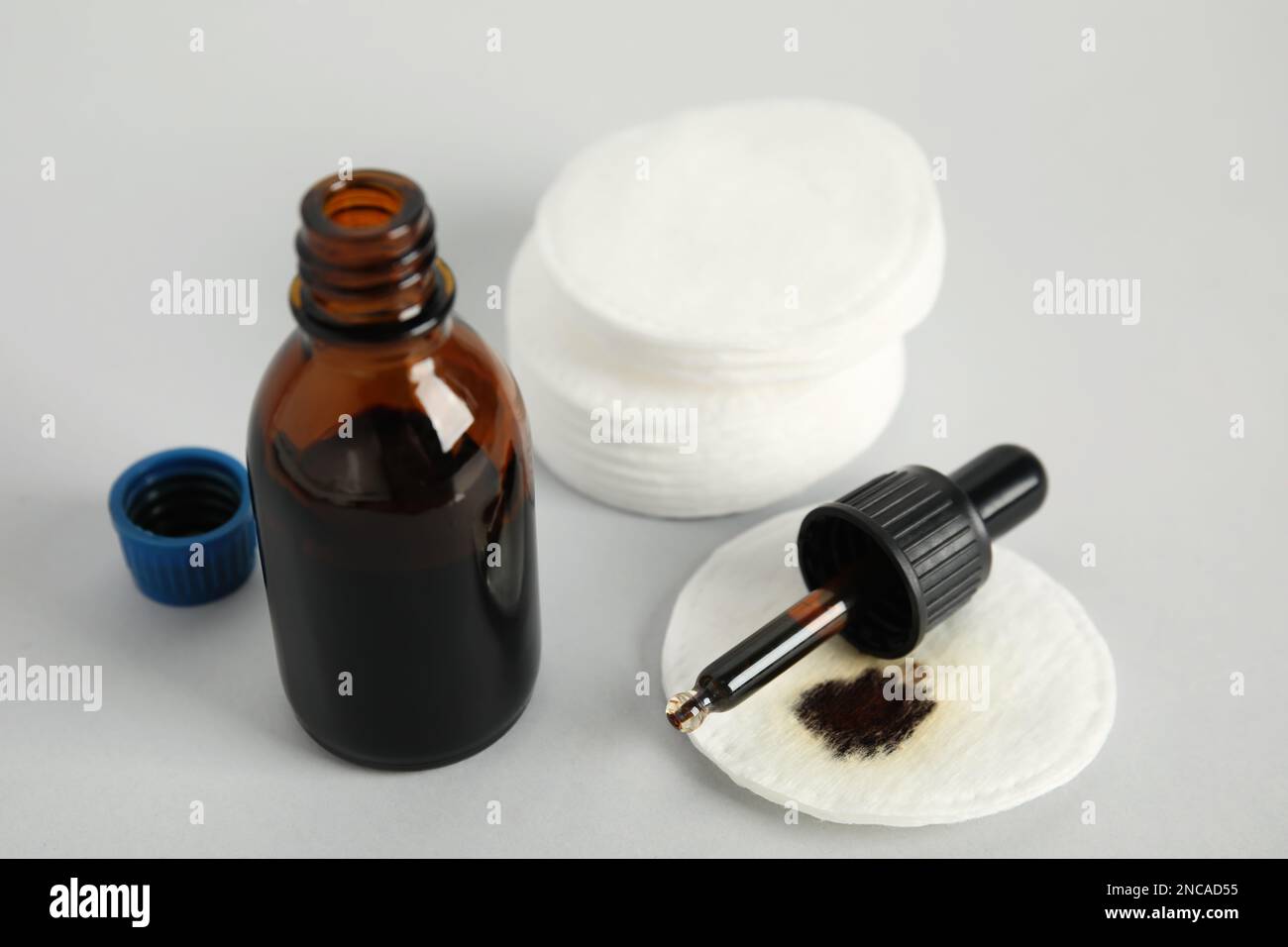 Bottle of medical iodine, dropper and cotton pads on grey background ...