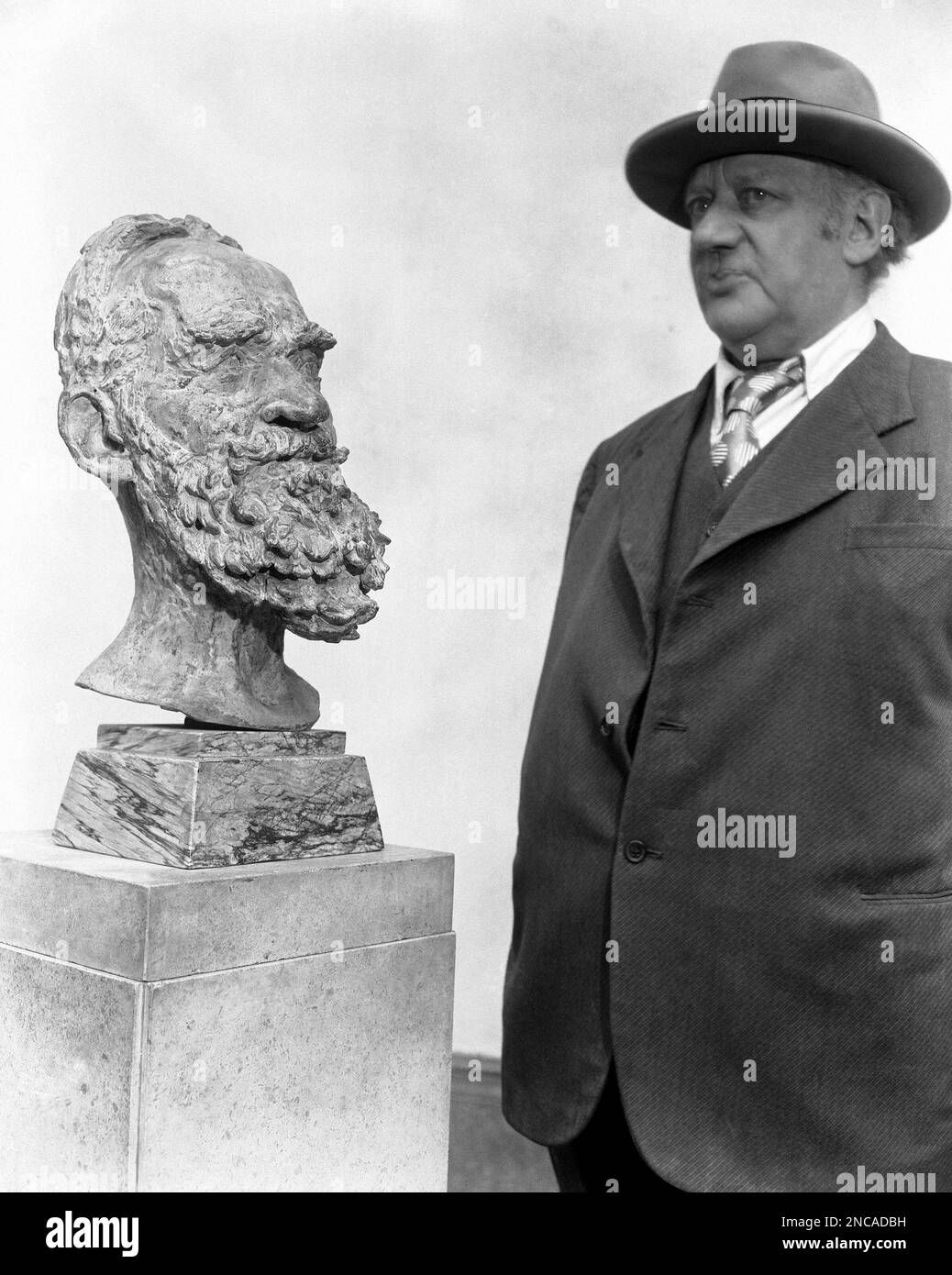 Famed sculptor Jacob Epstein stands beside a statue of playwright ...