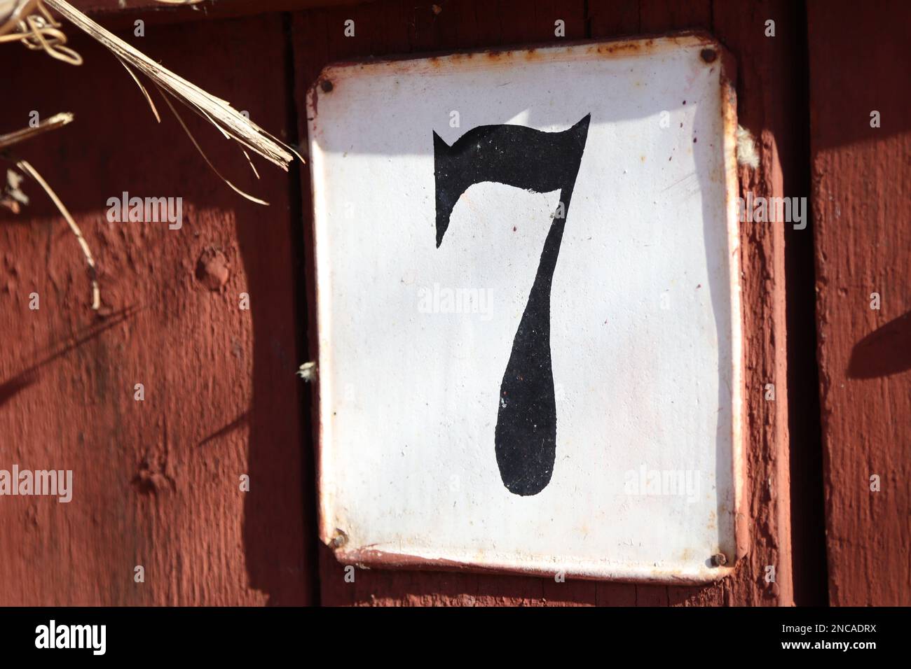 metallic black number seven 7 on white background on a red wooden wall ...