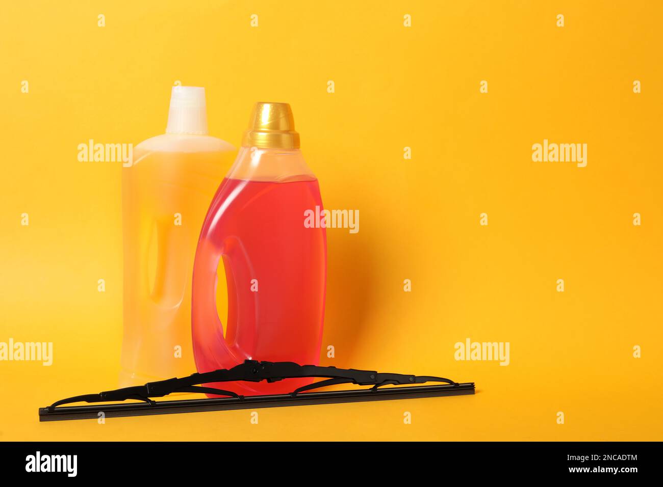 Bottles of windshield washer fluids and wiper on yellow background ...