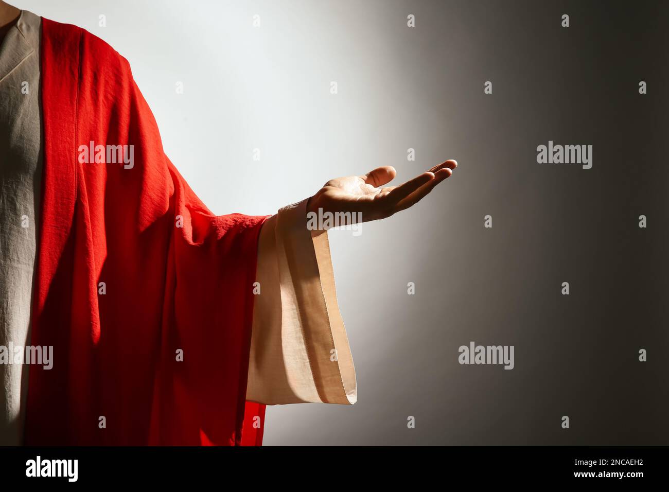 Jesus Christ reaching out his hand on grey background, closeup view ...