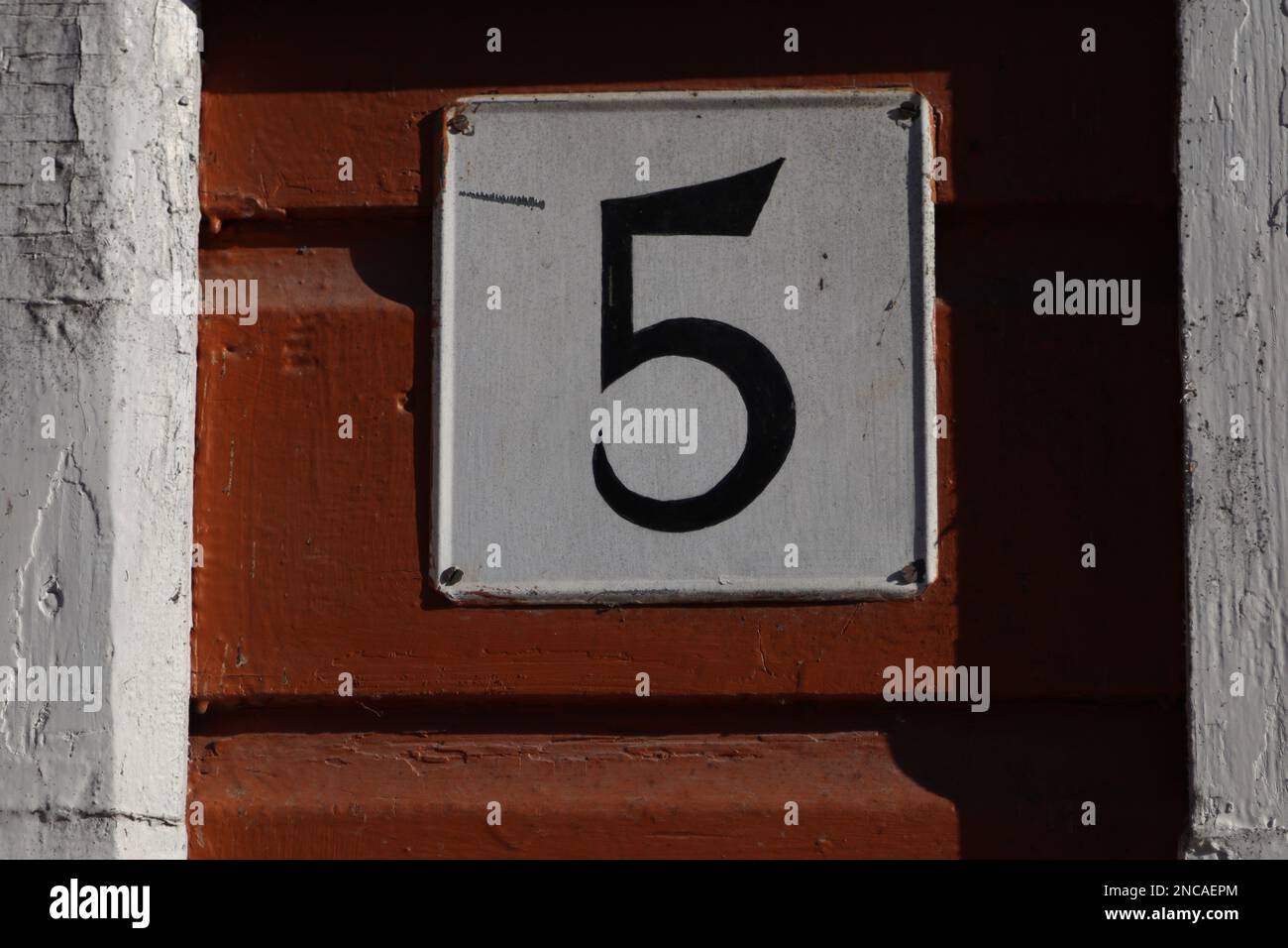 House number five. metal black lettering on a white background on a red ...