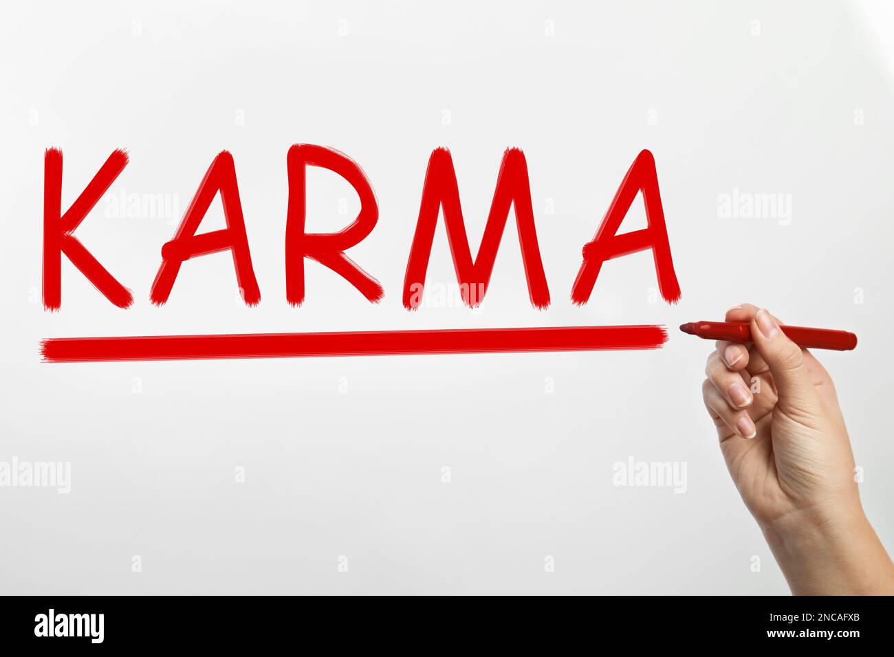 Woman writing word KARMA on glass against white background, closeup ...