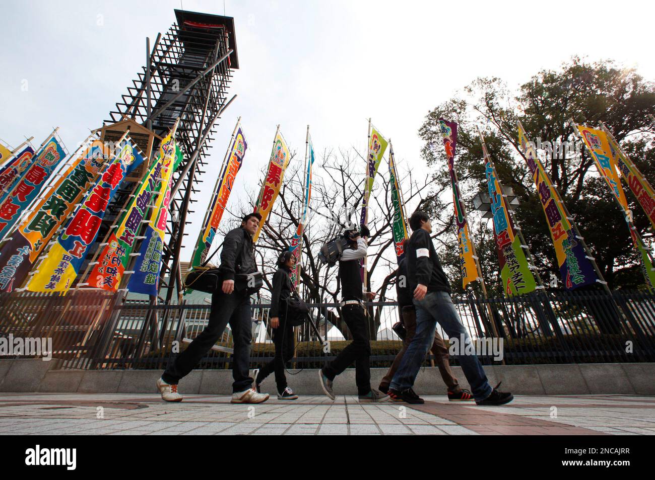 TV crew members walk past colorful flags with sumo wrestlers' names at ...