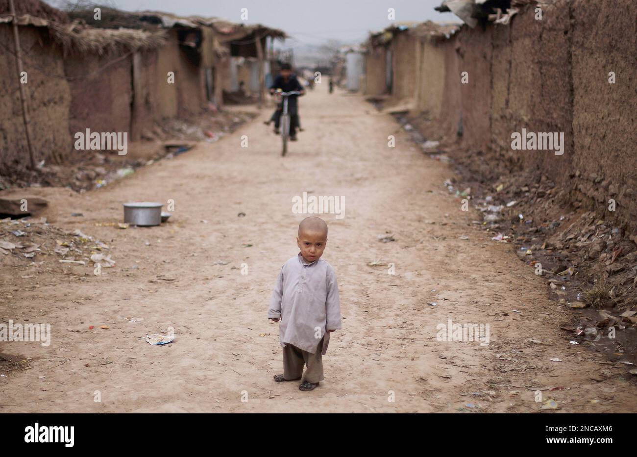 A young Afghan refugee boy looks on as he stands in an alley in a slum ...