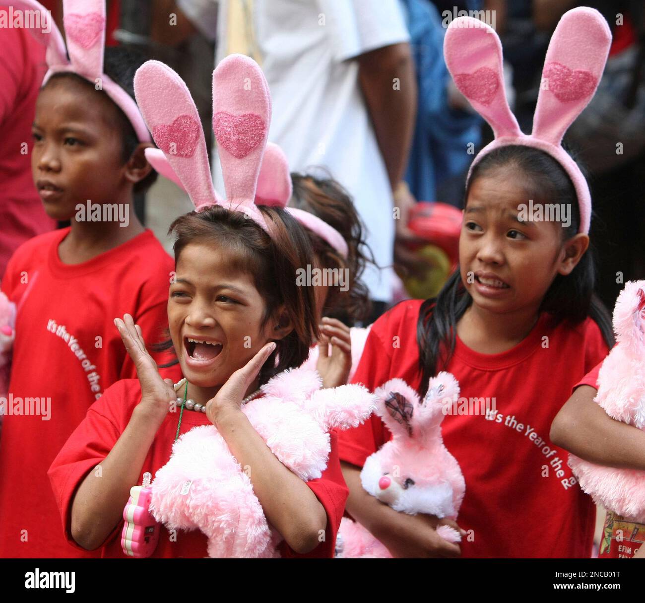 Children, wearing rabbit headbands, react to a performance during ...