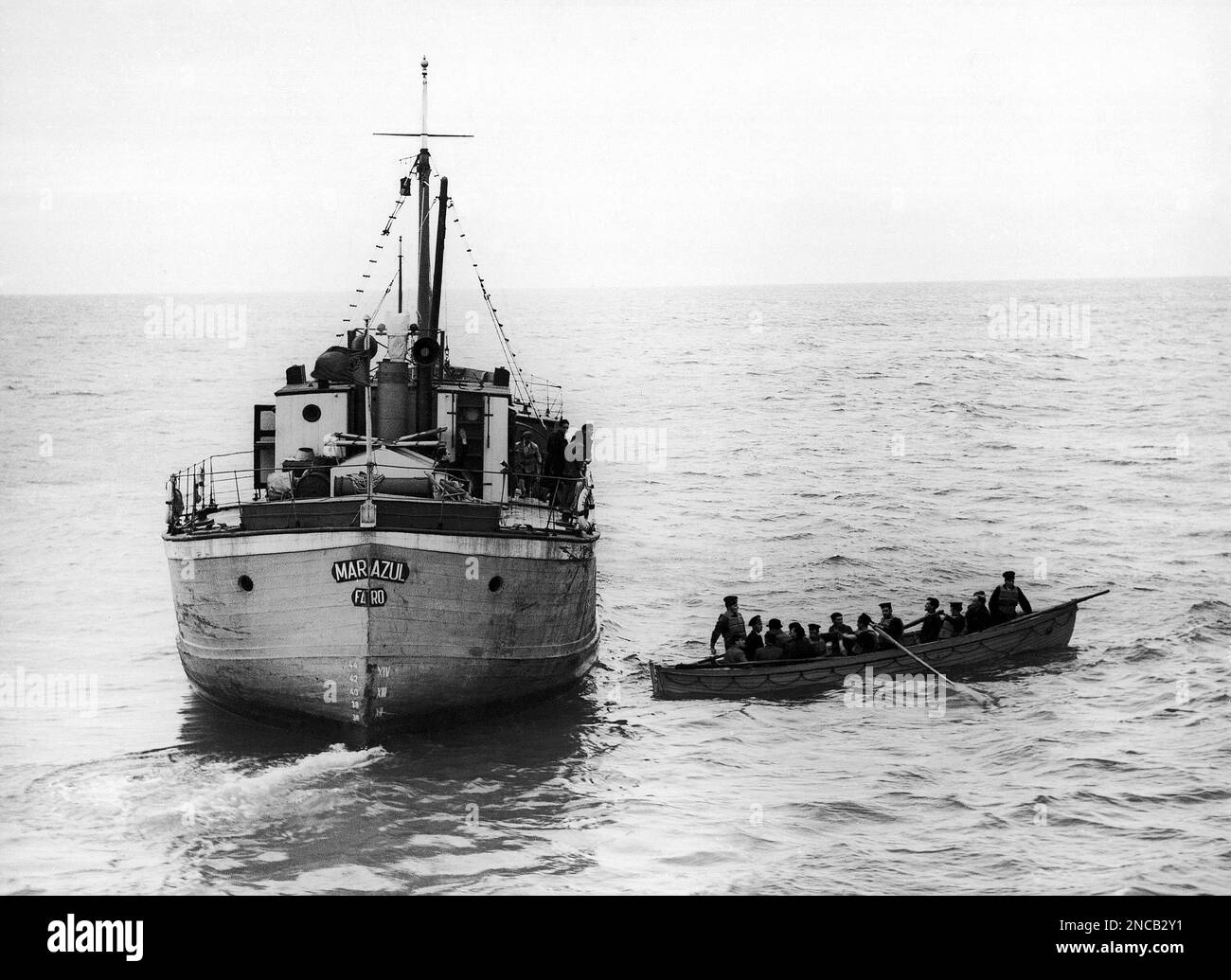Eighteen men standing on the rolling deck of a neutral cargo boat early ...