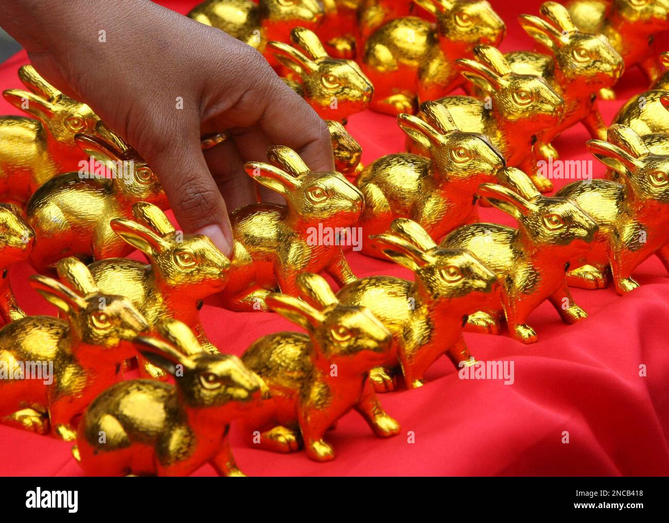 A vendor arranges her display of gold-plated rabbit as she peddles ...