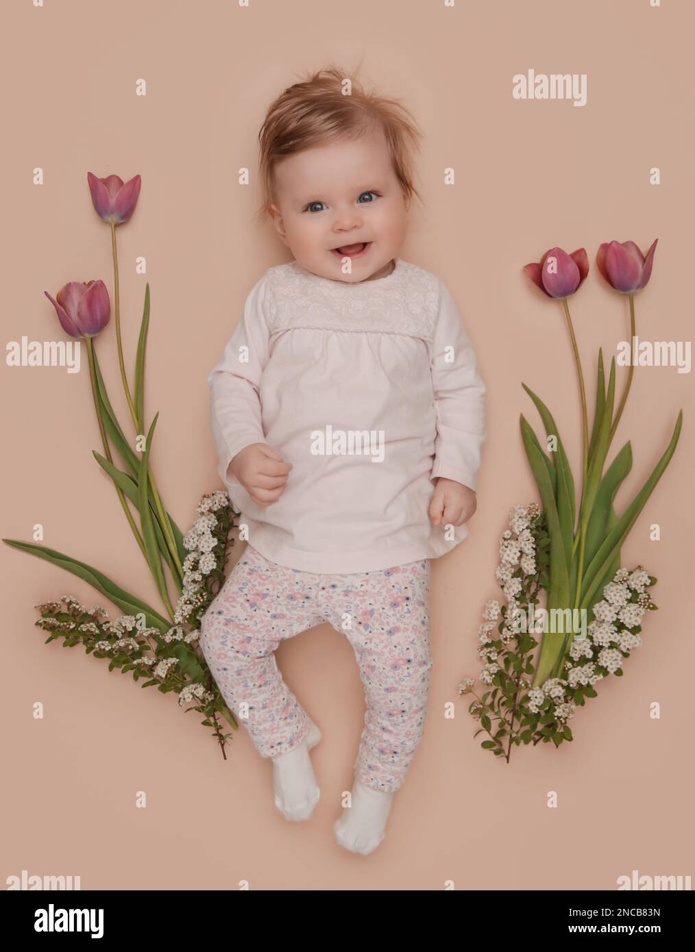 Adorable five months old baby with pink spring tulips. Herald of spring ...