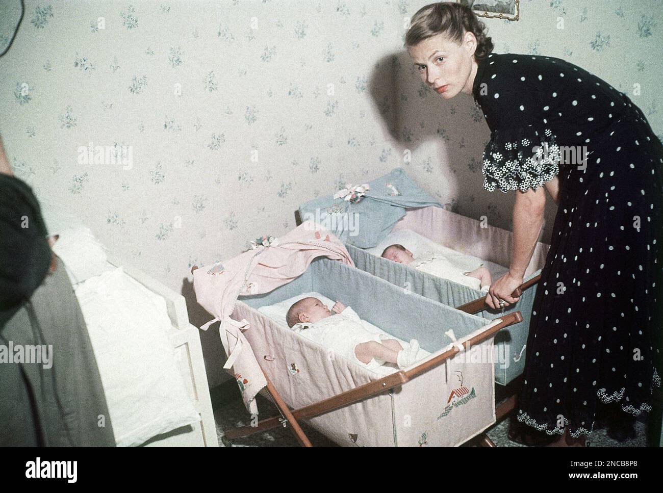 Actress Ingrid Bergman bending over the beds of her twins, left, Ingrid ...