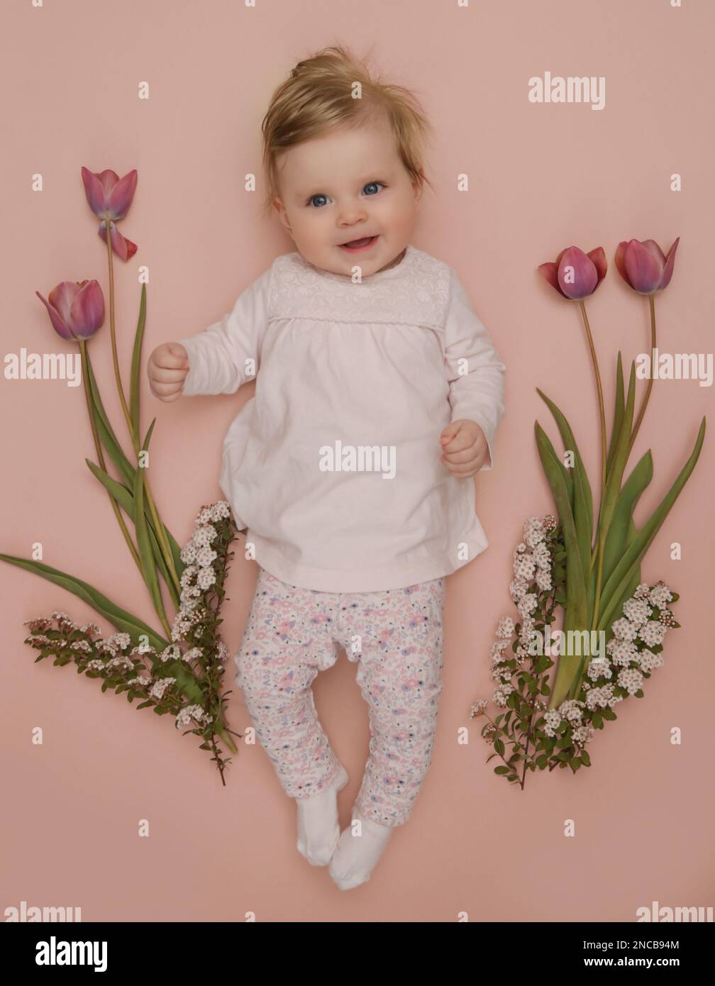 Adorable five months old baby with pink spring tulips. Herald of spring ...