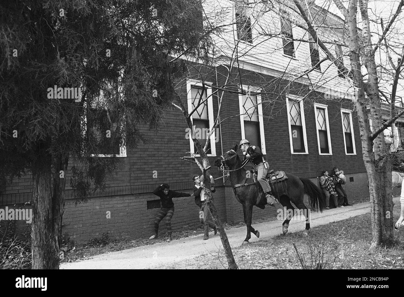 A mounted state trooper uses his club to prod two demonstrators who ...