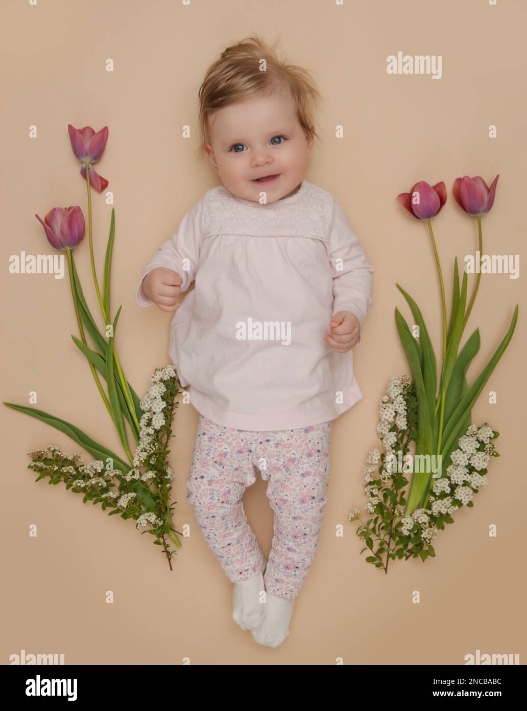 Adorable five months old baby with pink spring tulips. Herald of spring ...