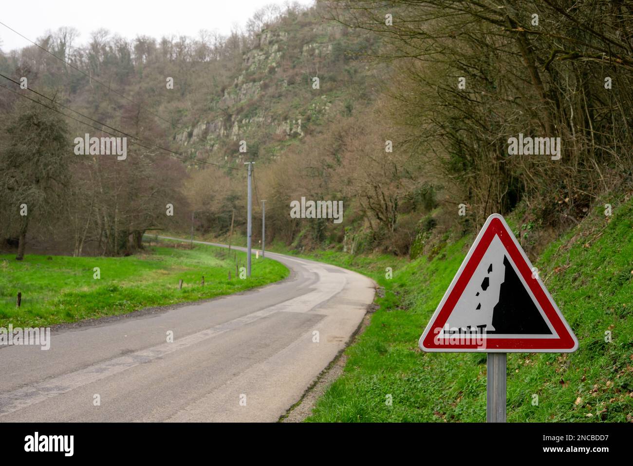 Road sign warning about falling stones and the road turning to the side ...