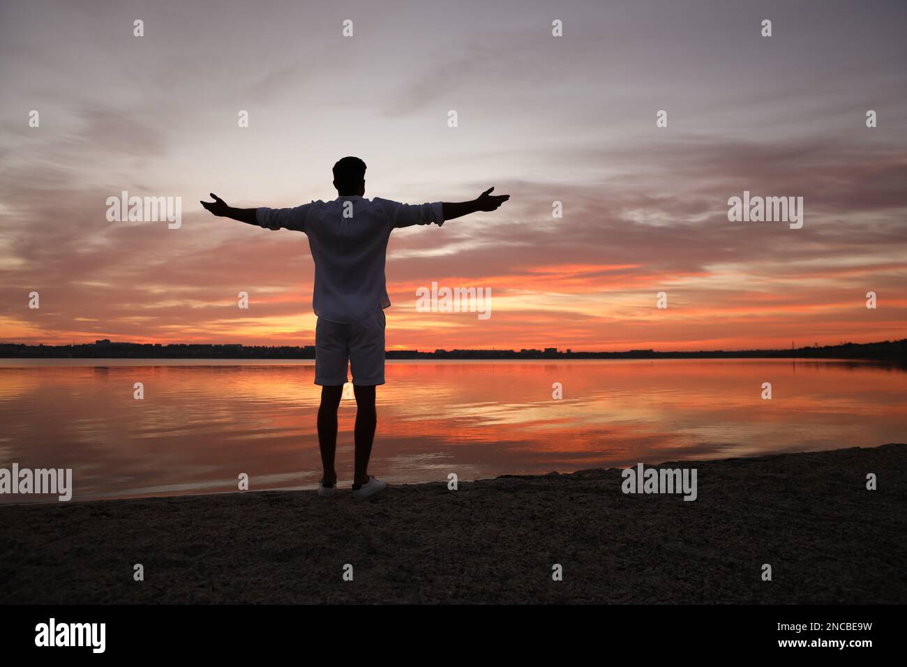 Man near river at sunset, back view. Nature healing power Stock Photo ...