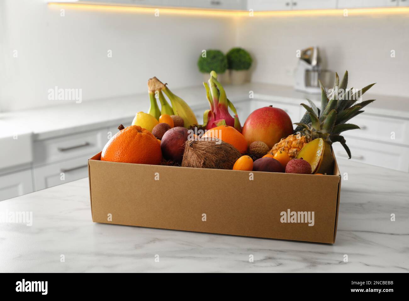 Cardboard box with assortment of exotic fruits on table in kitchen ...