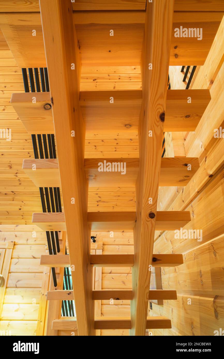 Underside view of staircase with wooden posts and black metal tubular ...