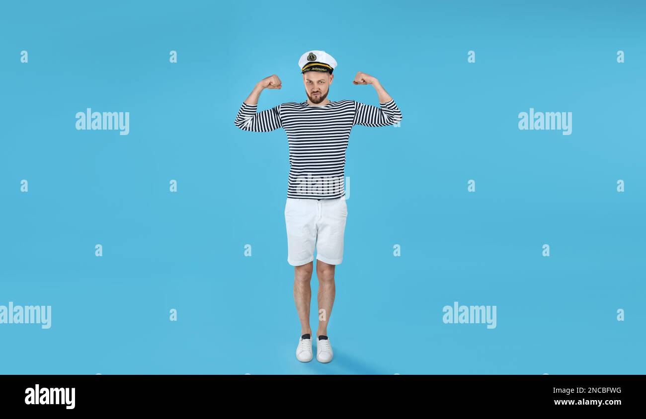 Strong sailor showing biceps on light blue background Stock Photo - Alamy