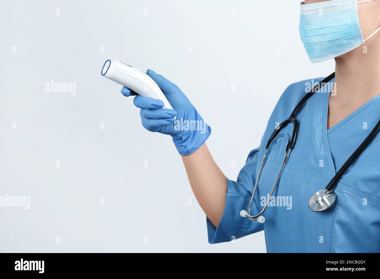 Doctor with infrared thermometer on light background, closeup. Checking ...