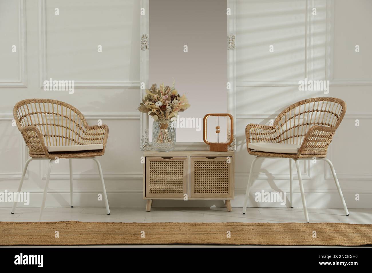 Living room interior with wooden commode, mirror and wicker chairs ...