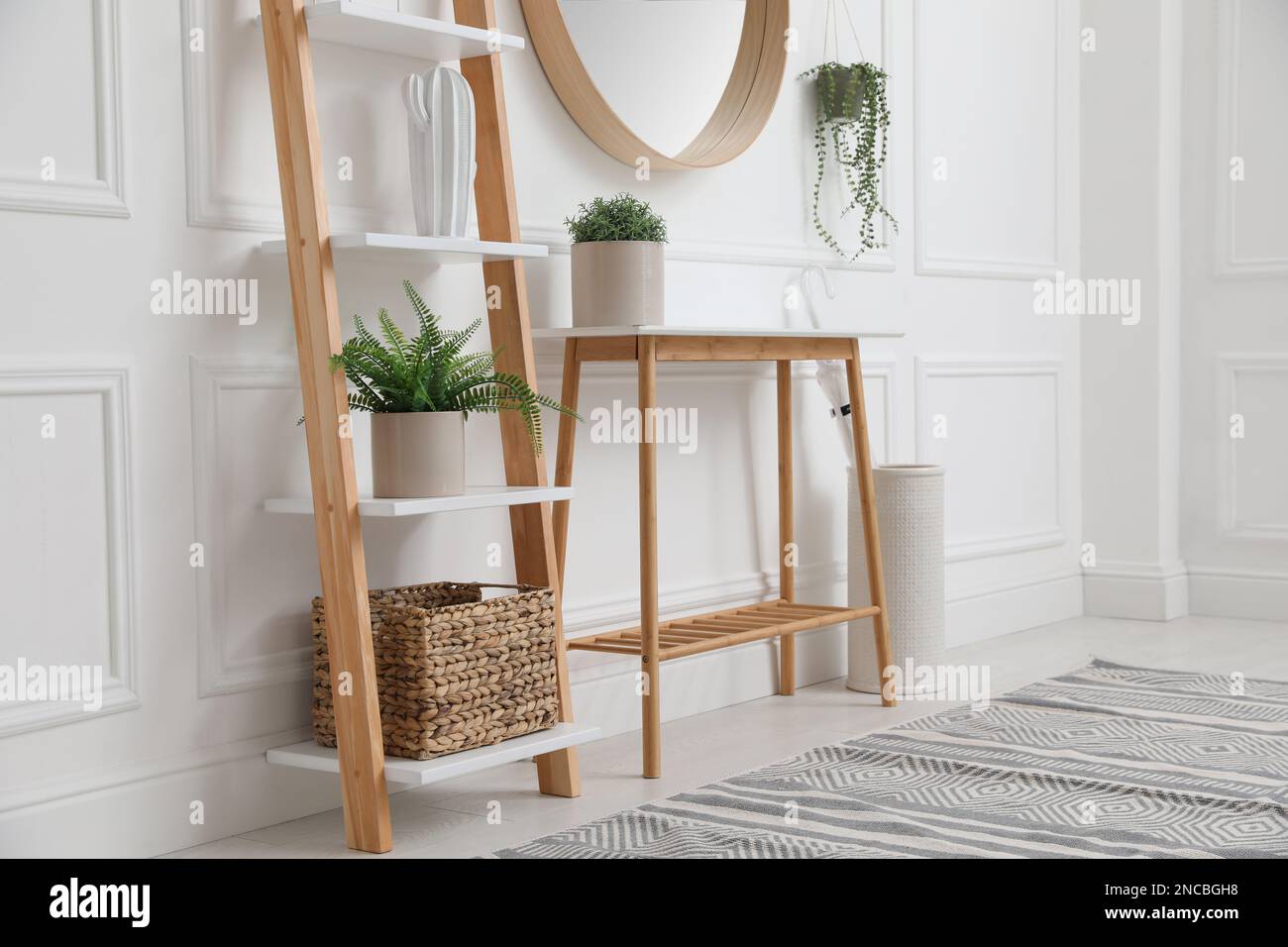 Console table with shelving unit and mirror on white wall in hallway ...