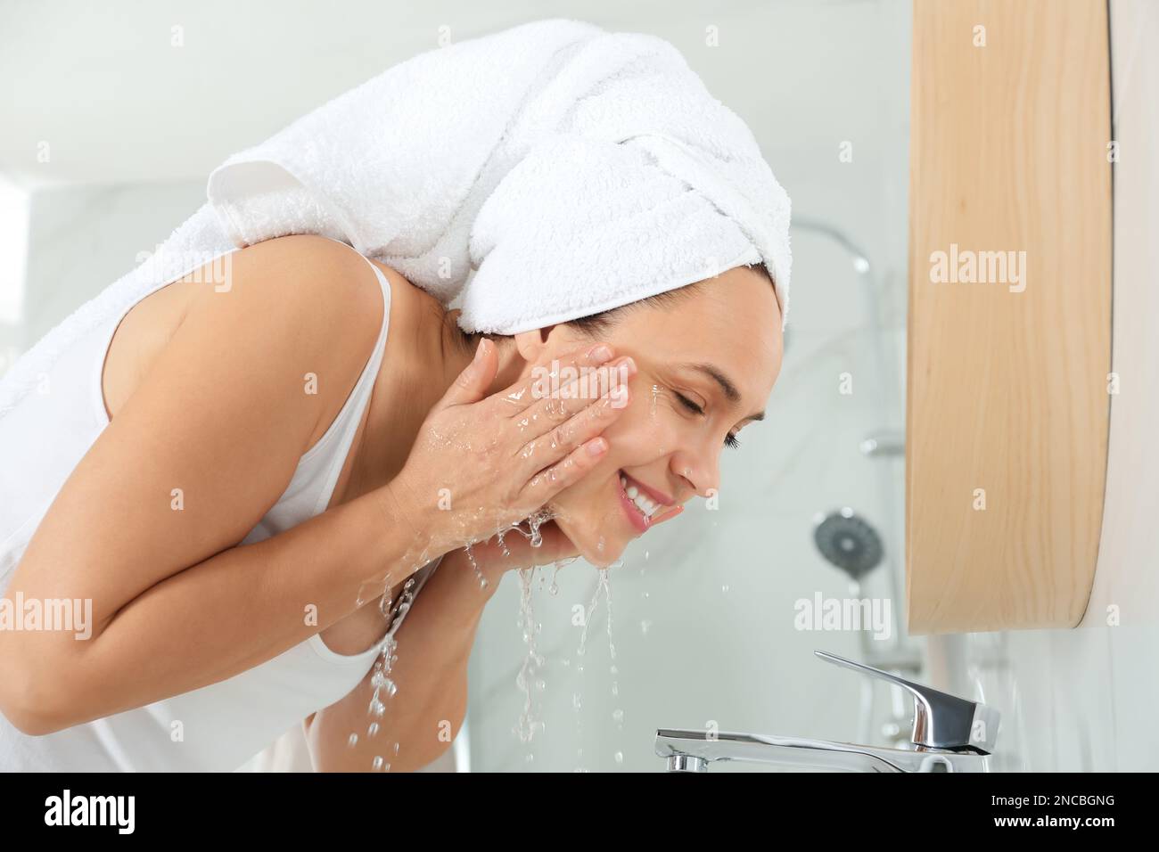 Happy mature woman washing face in bathroom Stock Photo - Alamy