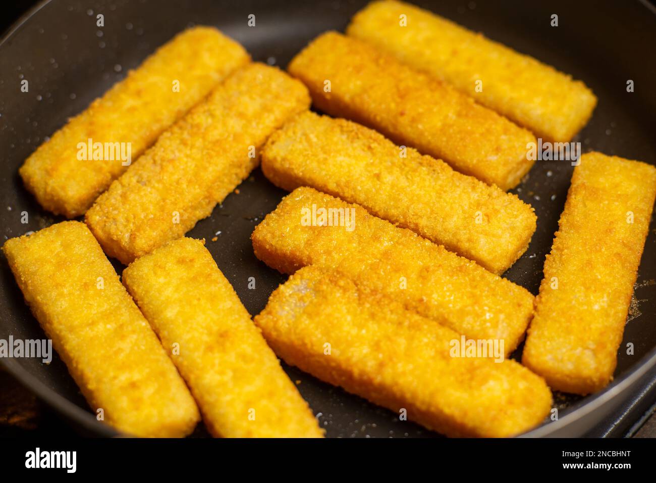 Fish sticks in a pan. Preparation of frozen fish sticks. Fast food ...