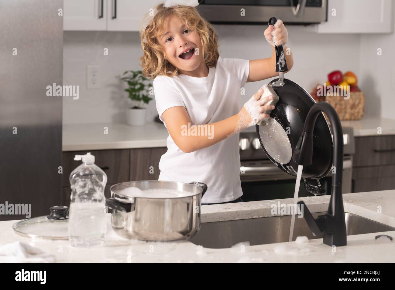 Child help in washing dishes at kitchen. Clean washed dishes ...
