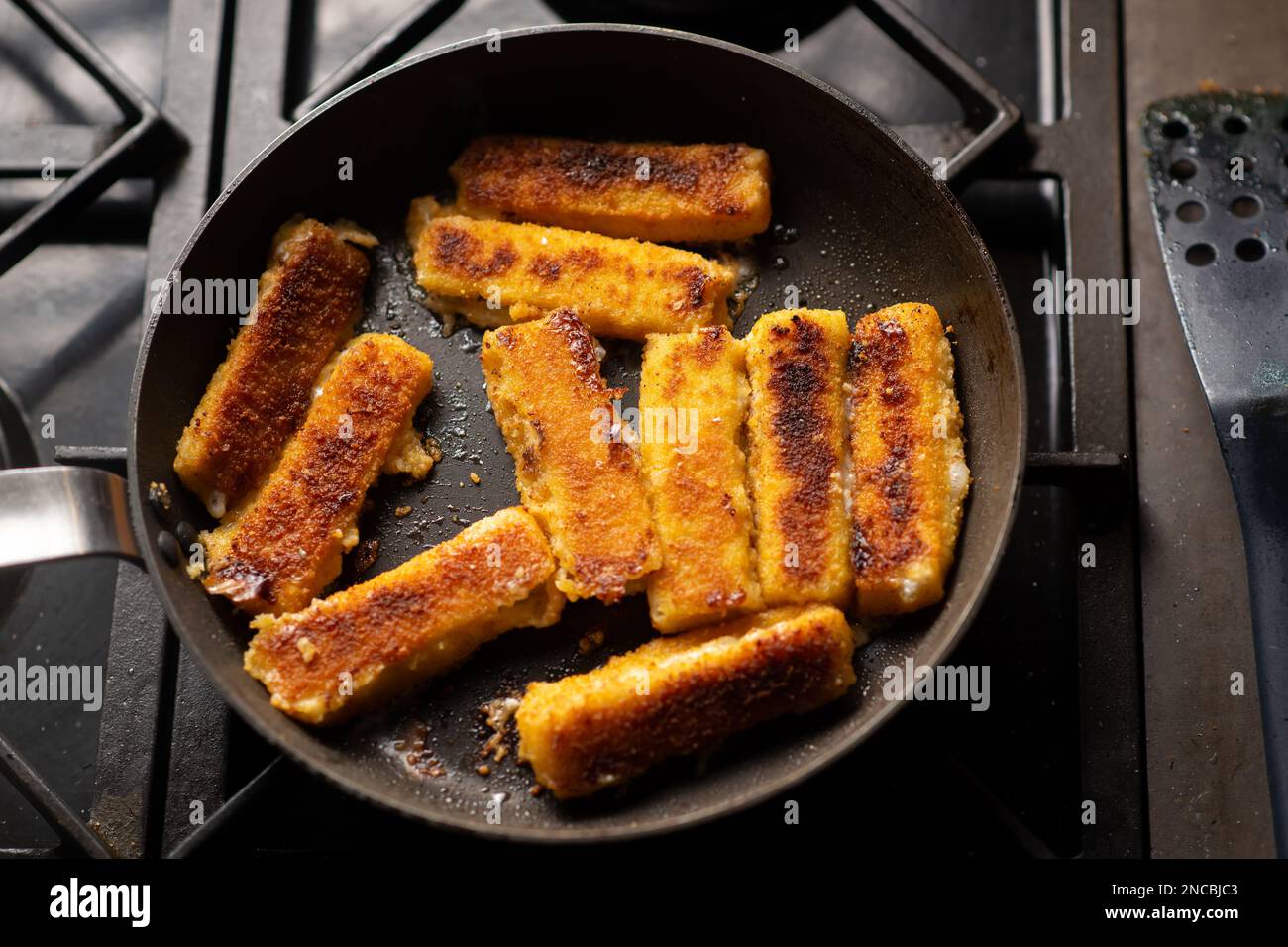 Fried fish sticks breaded in a frying pan. Preparation of frozen fish ...