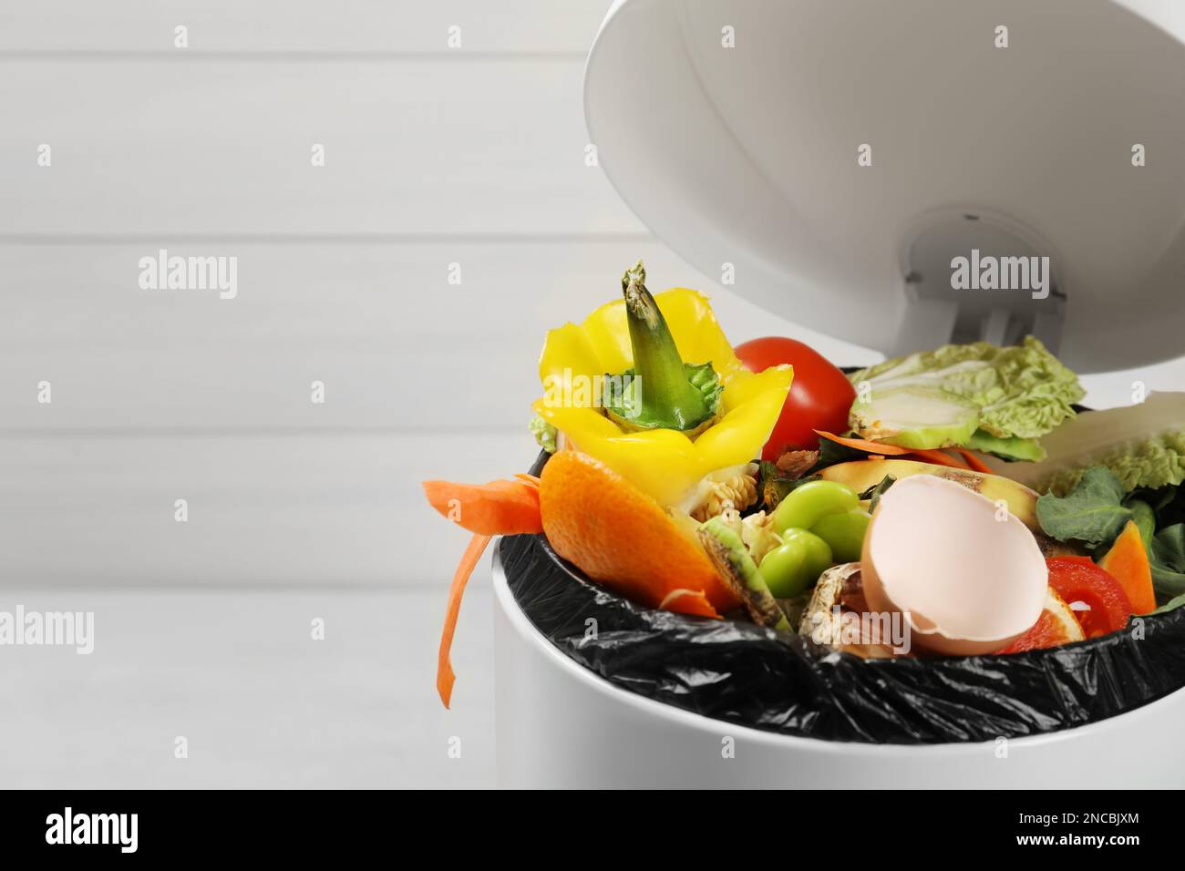 Natural garbage in trash bin on light background, closeup with space ...