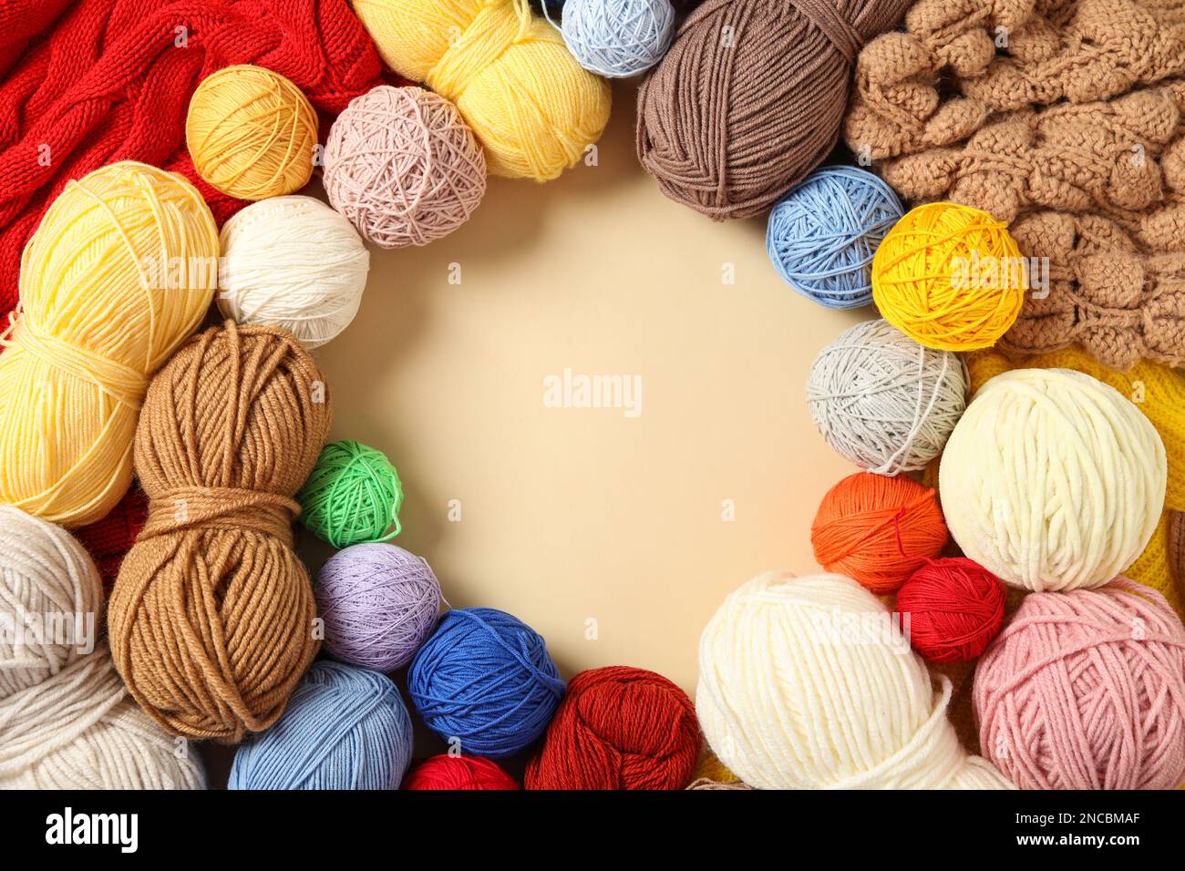 Frame of colorful woolen yarns on beige background, flat lay. Space for ...