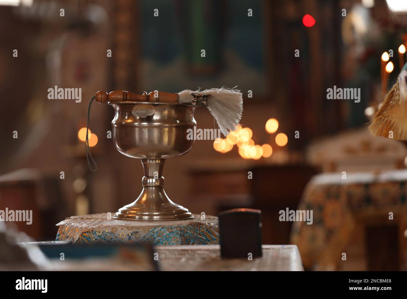 Silver vessel with holy water and brush on stand in church. Baptism ...