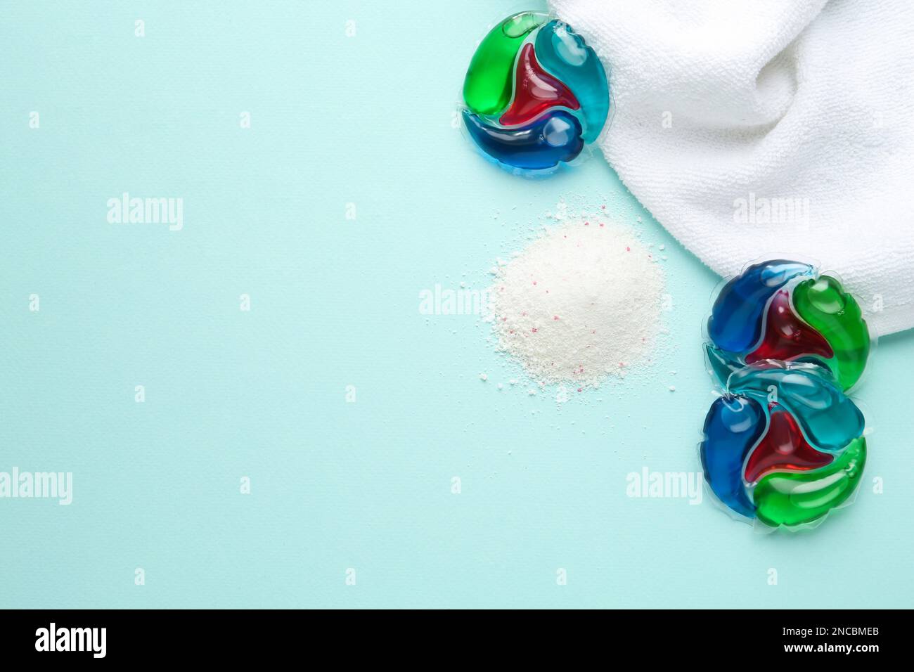 Laundry capsules, detergent powder and towel on turquoise background ...