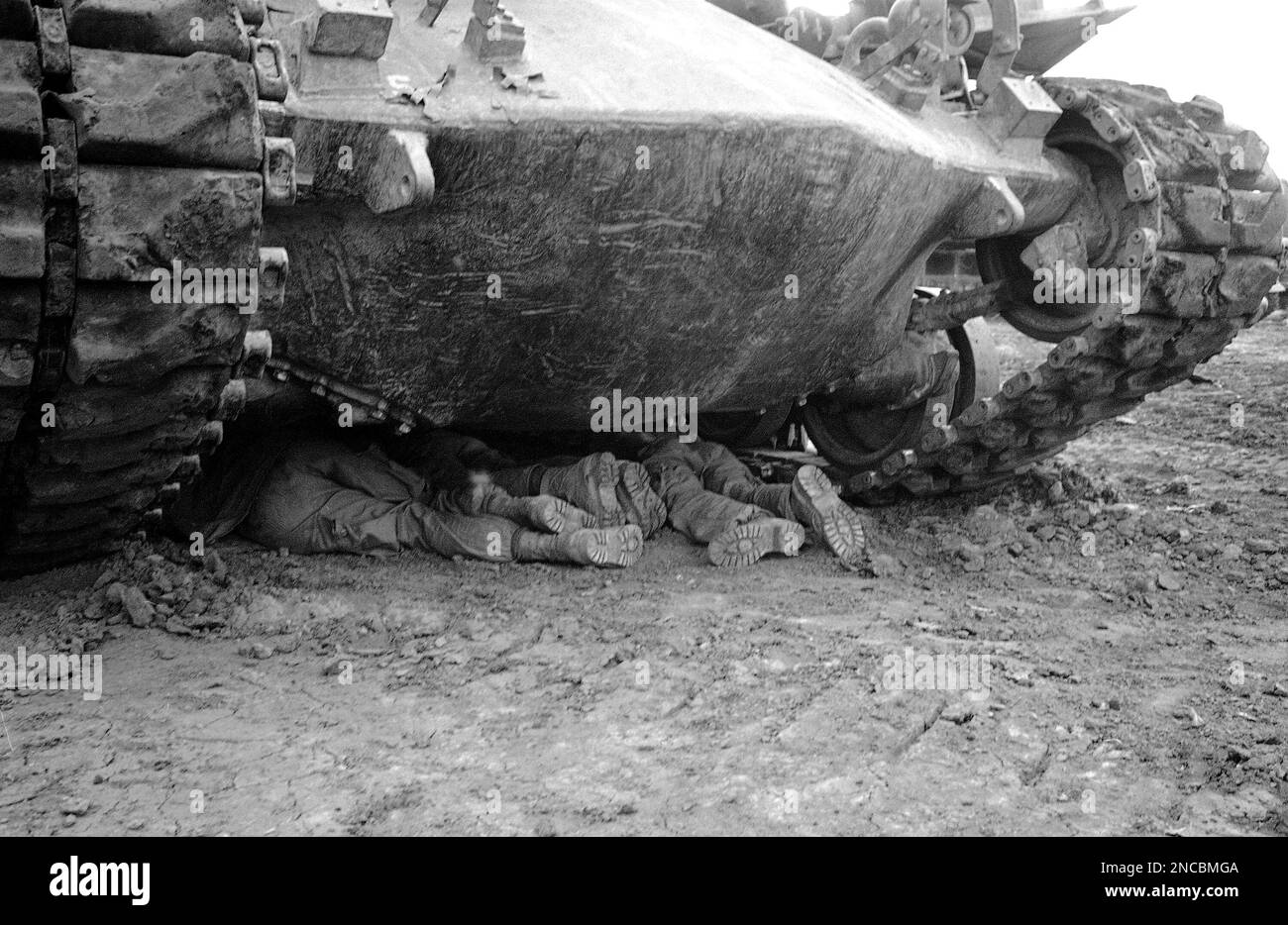 Feet and legs of three U.S. soldiers stick out from under steel hull of ...