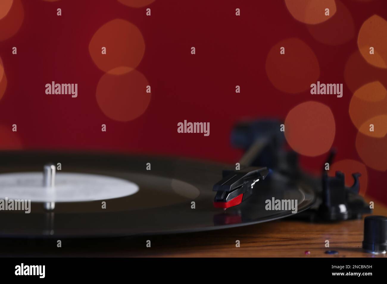 Vinyl record on turntable against blurred lights, closeup. Space for ...